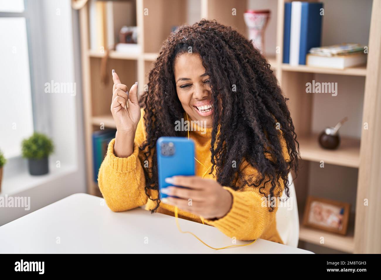 Plus size hispanic woman using smartphone sitting on the table smiling ...
