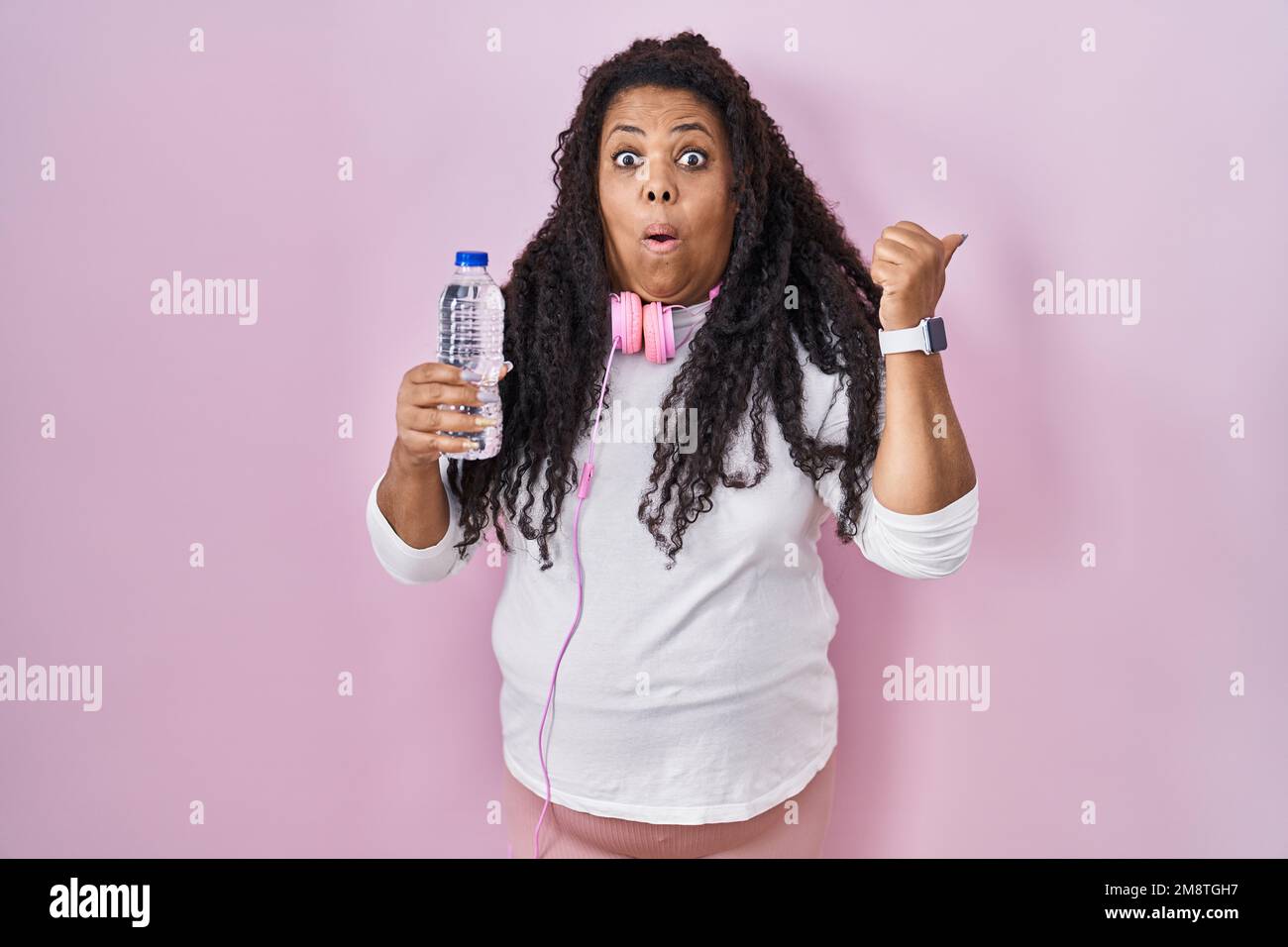 Plus size hispanic woman wearing sportswear and headphones surprised ...