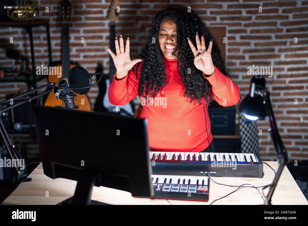 Plus size hispanic woman playing piano at music studio showing and ...