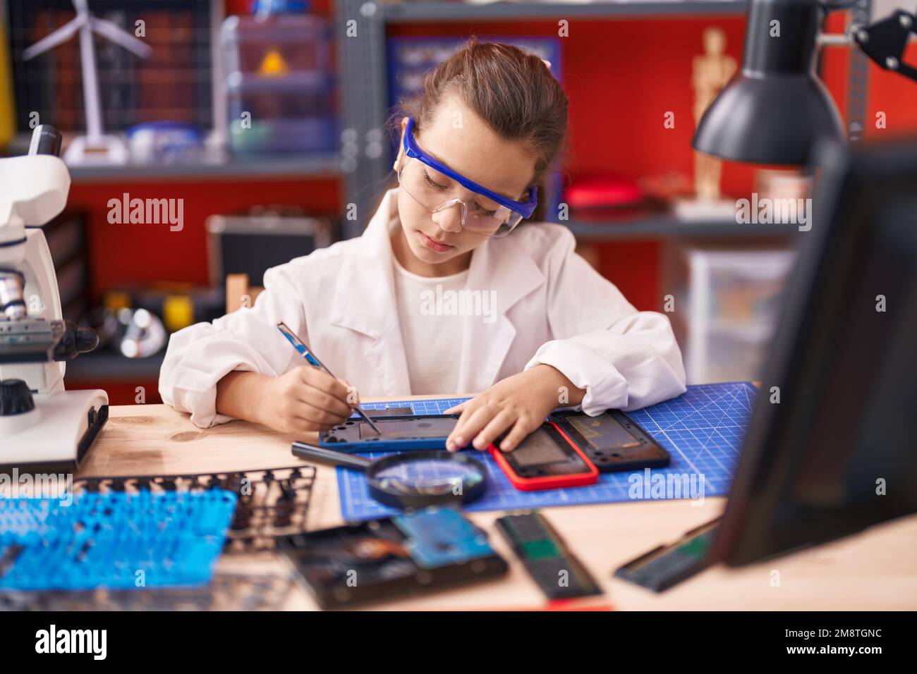 Adorable hispanic girl student repairing smartphone at classroom Stock ...