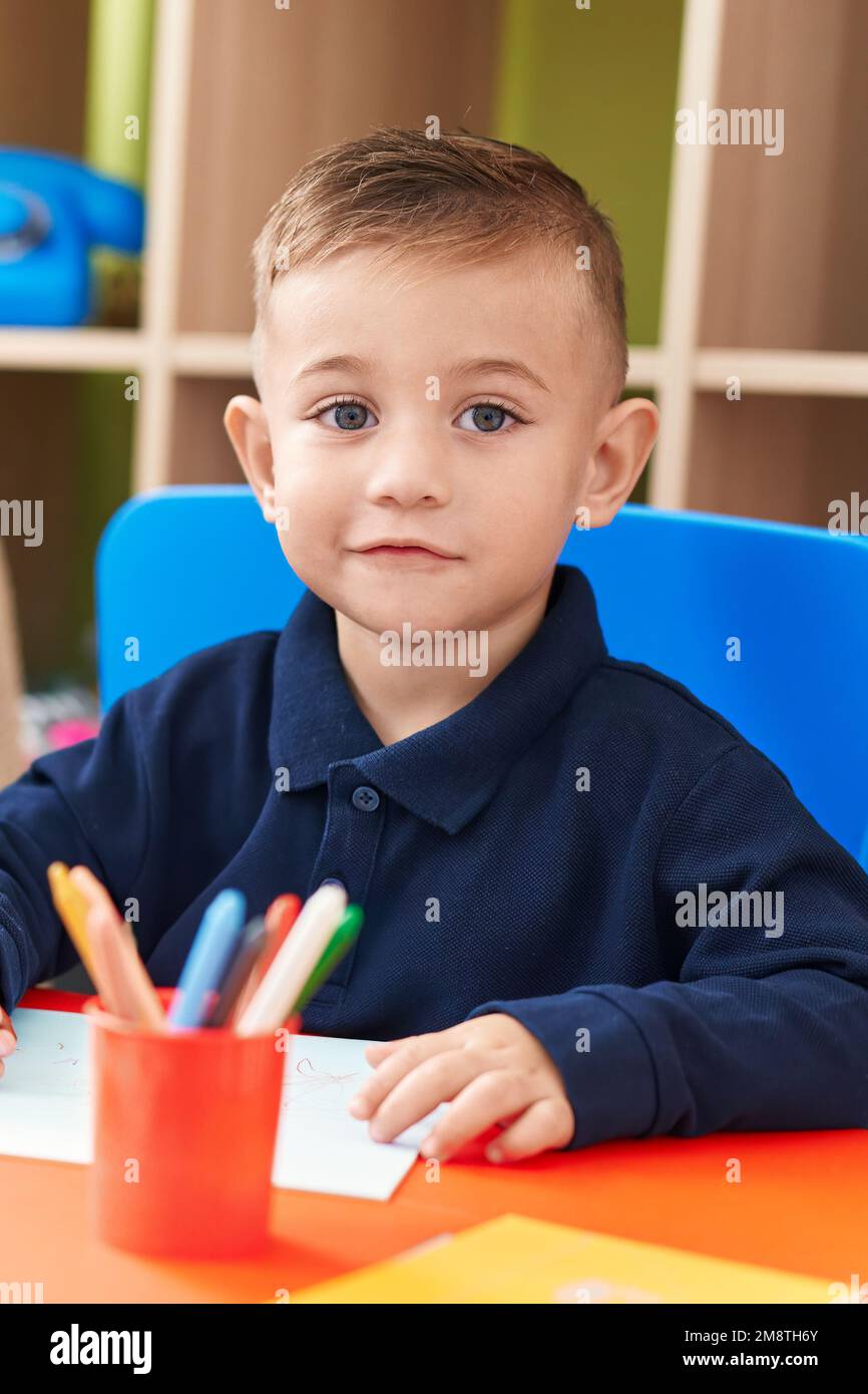 Adorable hispanic boy preschool student sitting on table drawing on ...