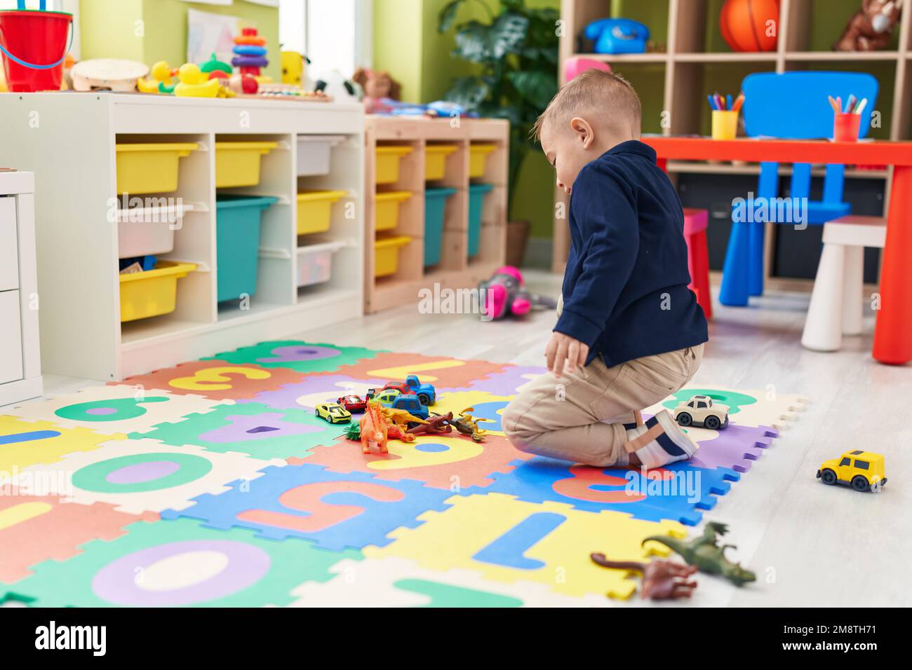 Adorable hispanic boy playing with cars toy sitting on floor at ...