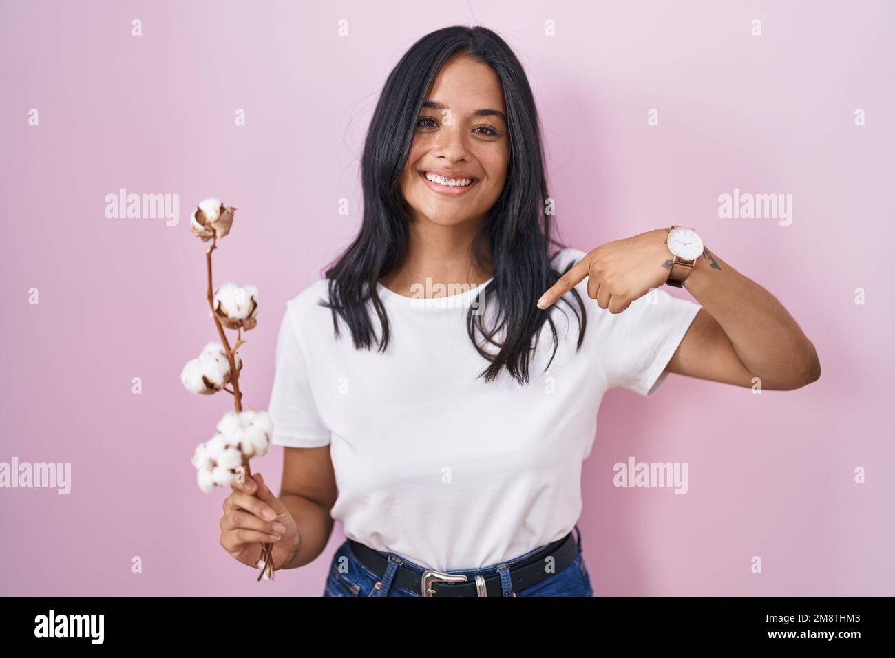 Brunette woman standing over pink background looking confident with ...