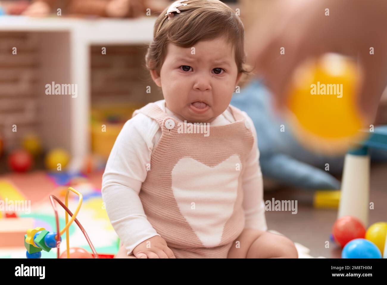 Adorable toddler sitting on floor looking ball crying at kindergarten ...