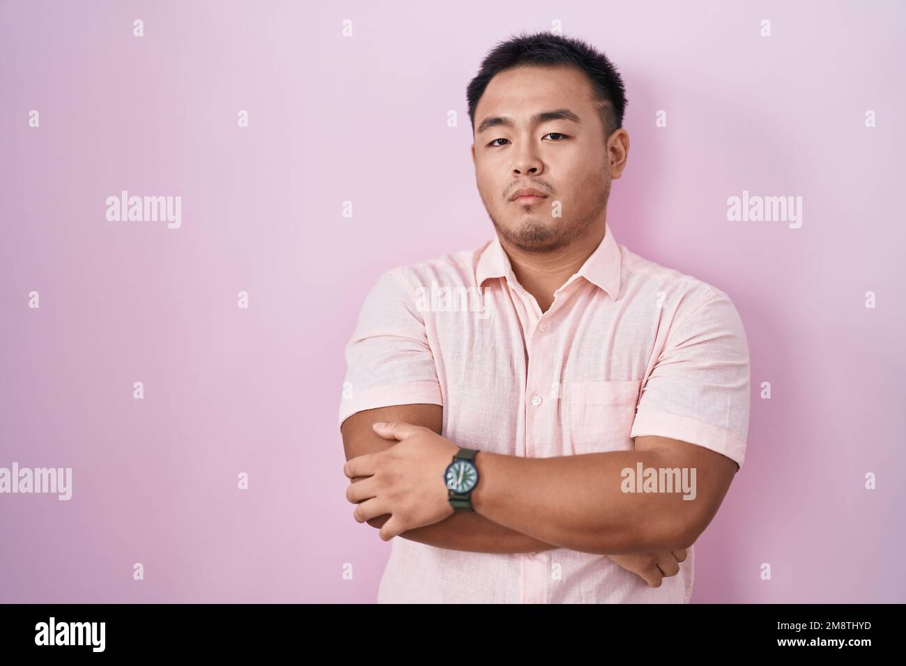 Chinese young man standing over pink background skeptic and nervous ...