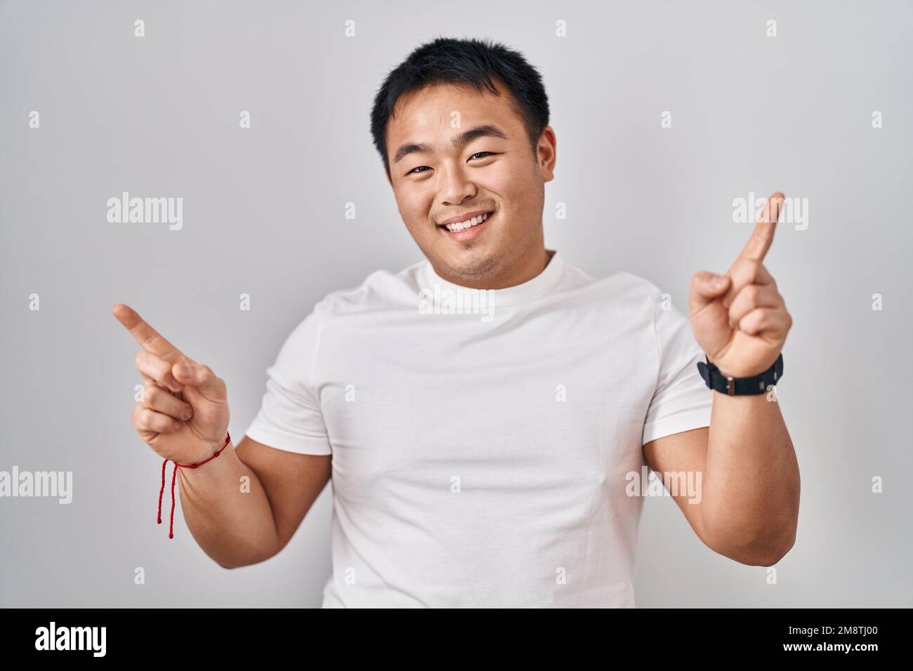 Young chinese man standing over white background smiling confident ...