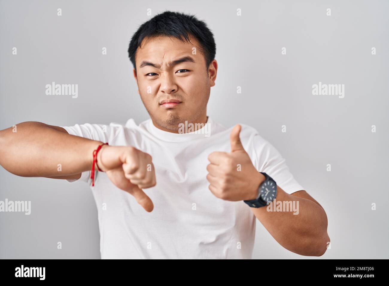 Young chinese man standing over white background doing thumbs up and ...