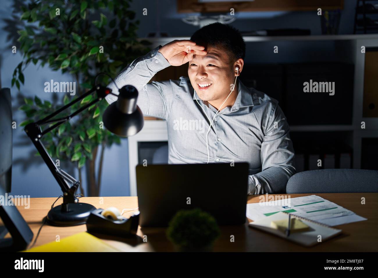 Young chinese man working using computer laptop at night very happy and ...