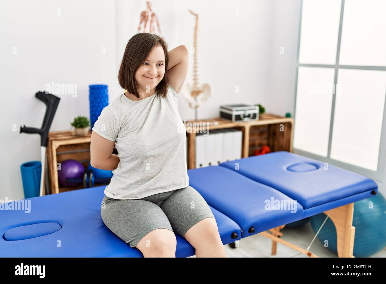 Brunette woman with down syndrome stretching arms at physiotherapy ...