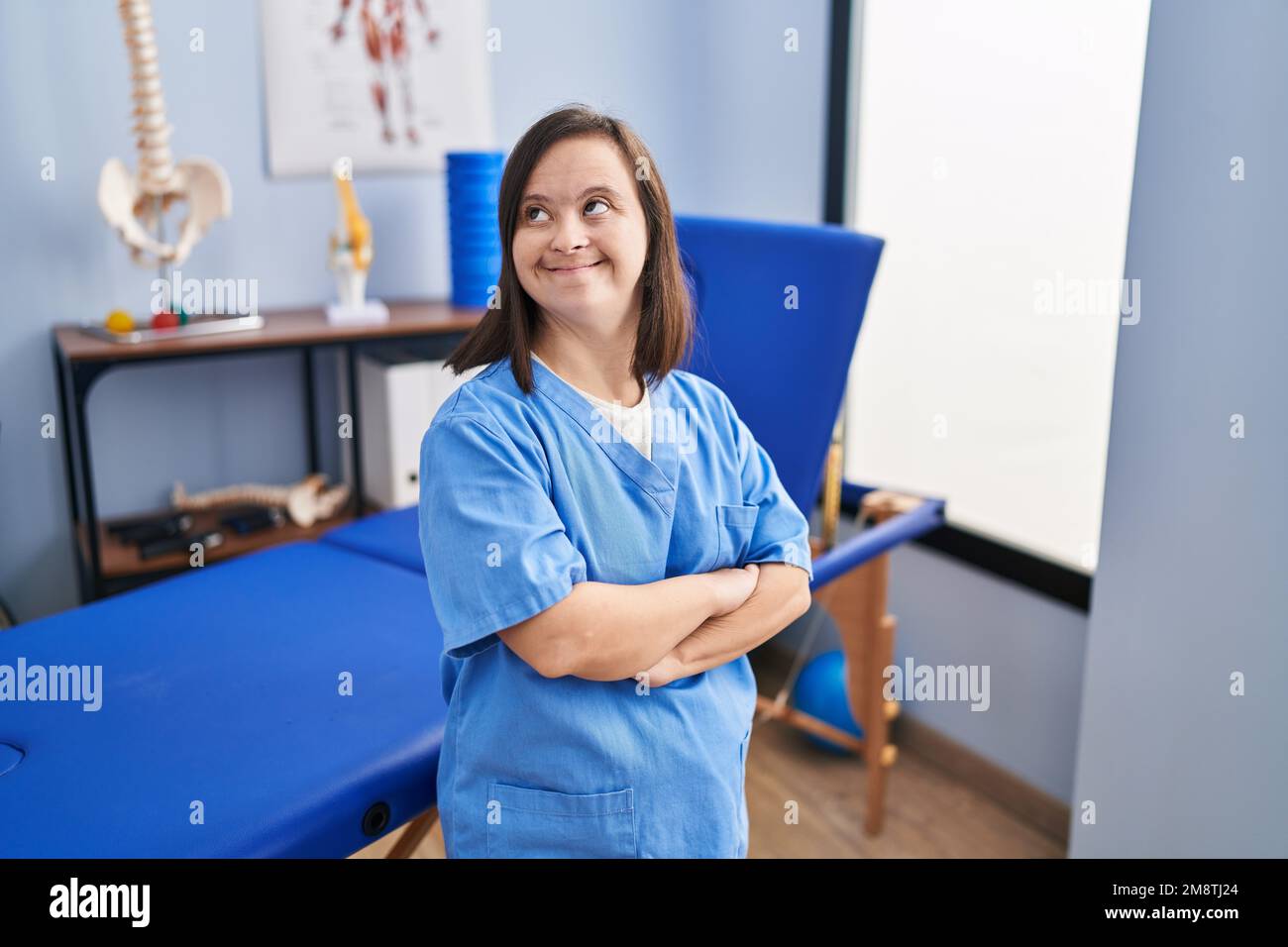 Down syndrome woman wearing physiotherapy uniform standing with arms ...