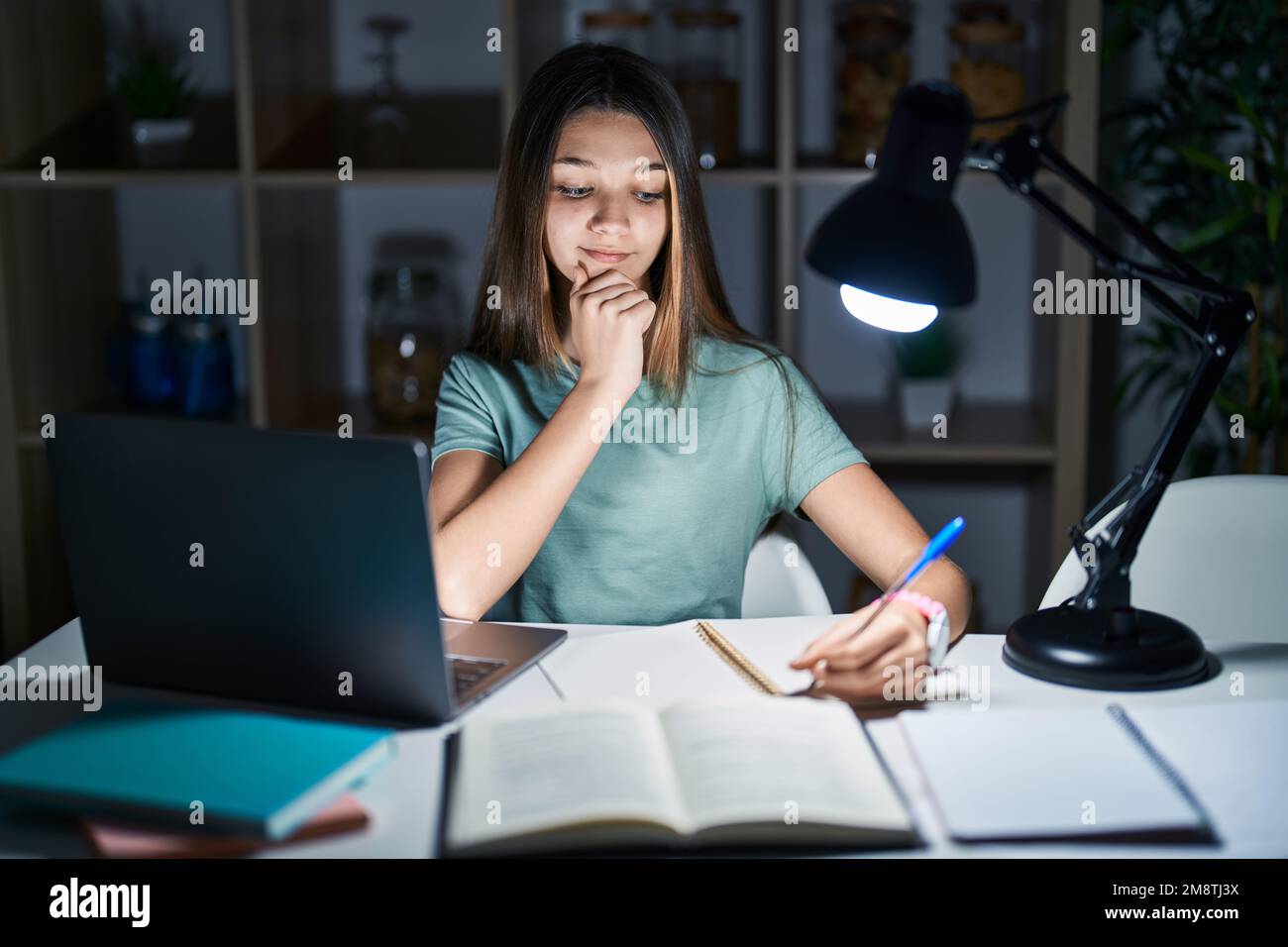 Teenager girl doing homework at home late at night looking confident at ...