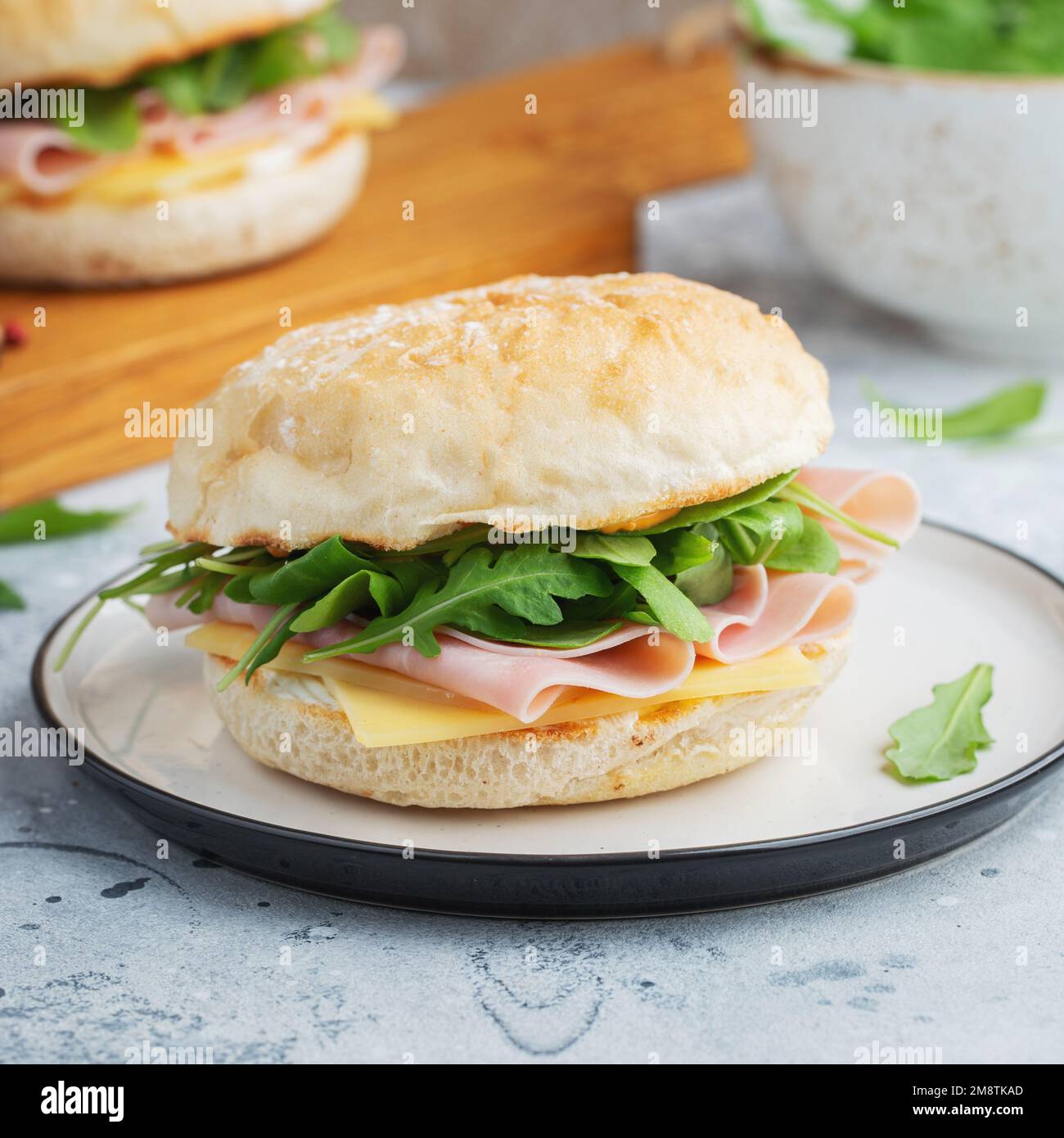 Two homemade sandwiches with ham, cheese and arugula on a concrete ...