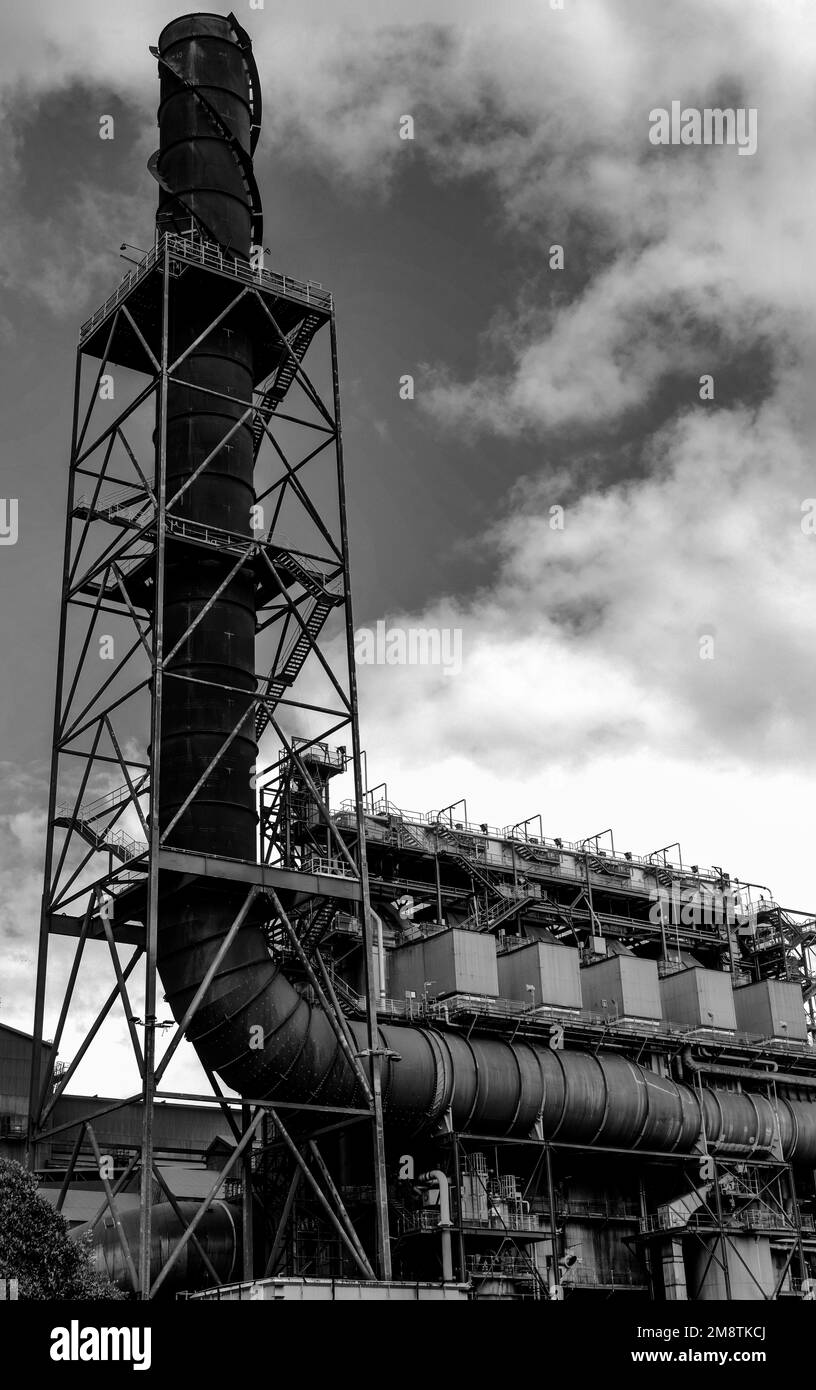 A vertical grayscale of the big chimney of the factory at the Port ...