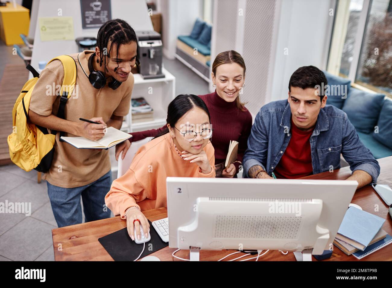 High angle view at diverse group of college students using computer together in library interior ...