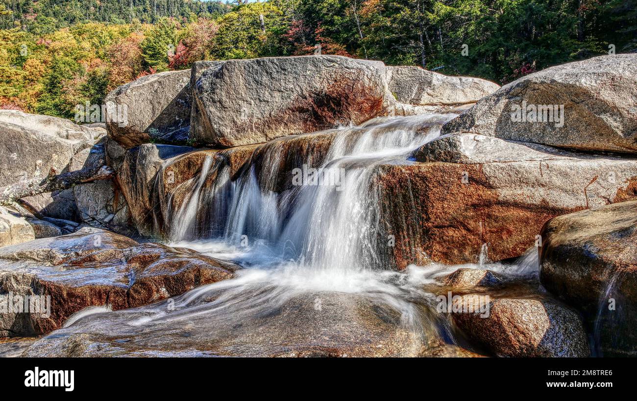 Rocks with blured water and autumn colors in distance Stock Photo - Alamy