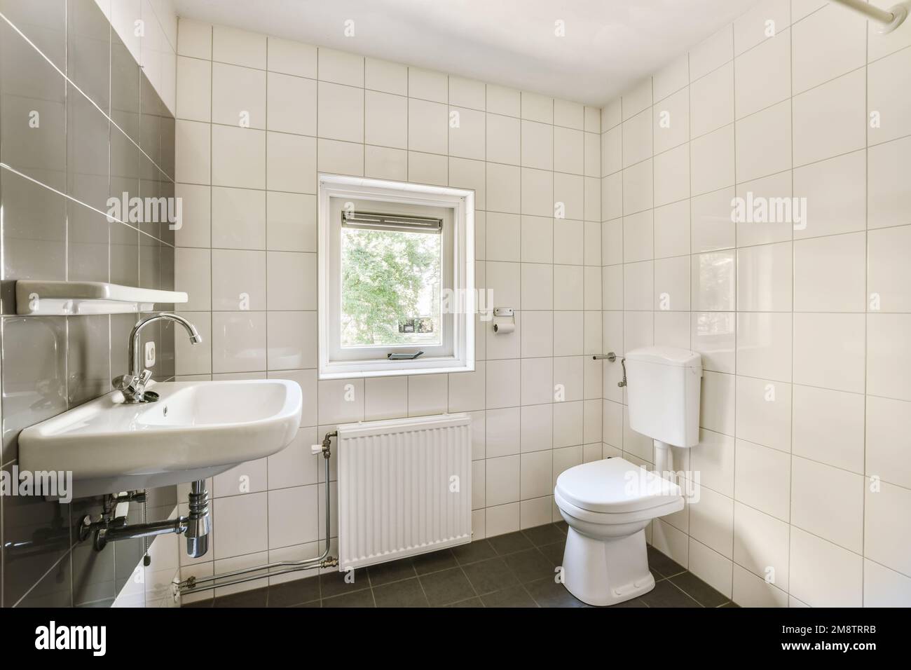 a bathroom with white tiles on the walls and black tile flooring around ...
