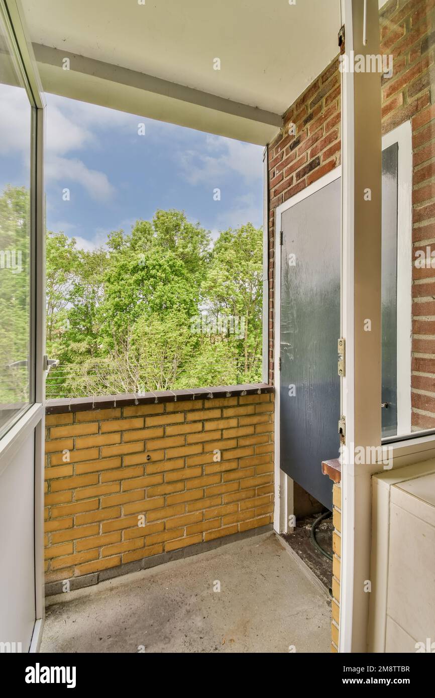 an empty balcony with brick wall and door leading out to the trees in ...