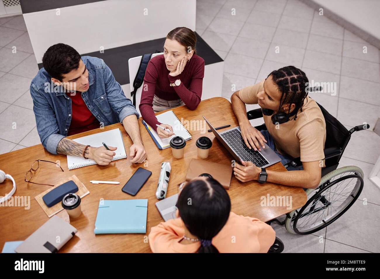 Top view at diverse group of young people studying together at table in ...