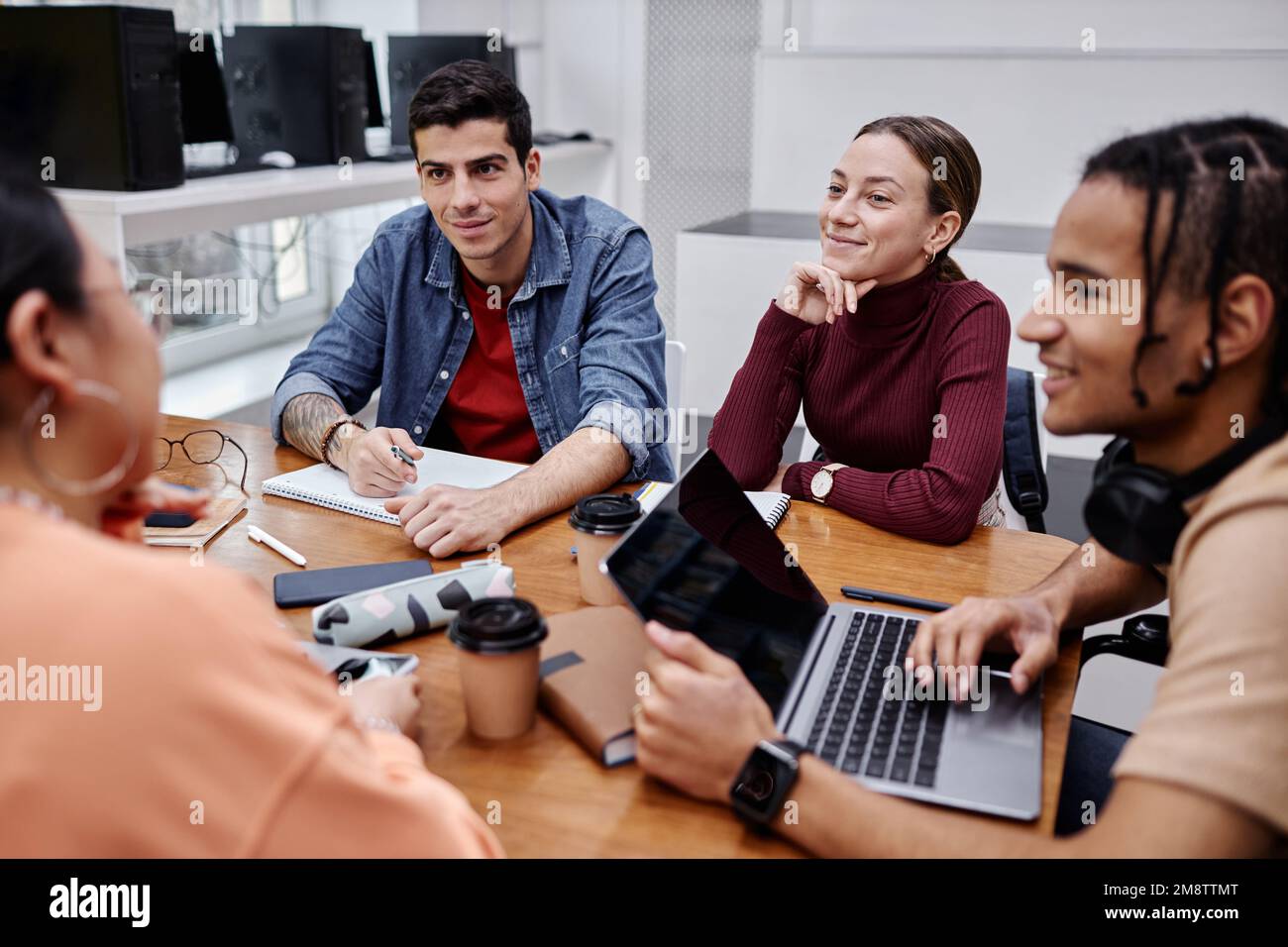 Diverse group of students studying together at table in college lounge ...