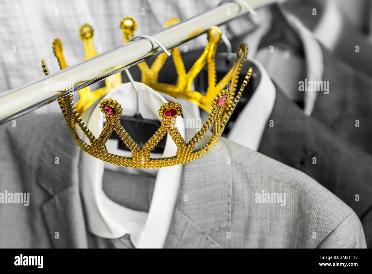 Business suit with a gold crown hanging on a hanger Stock Photo - Alamy
