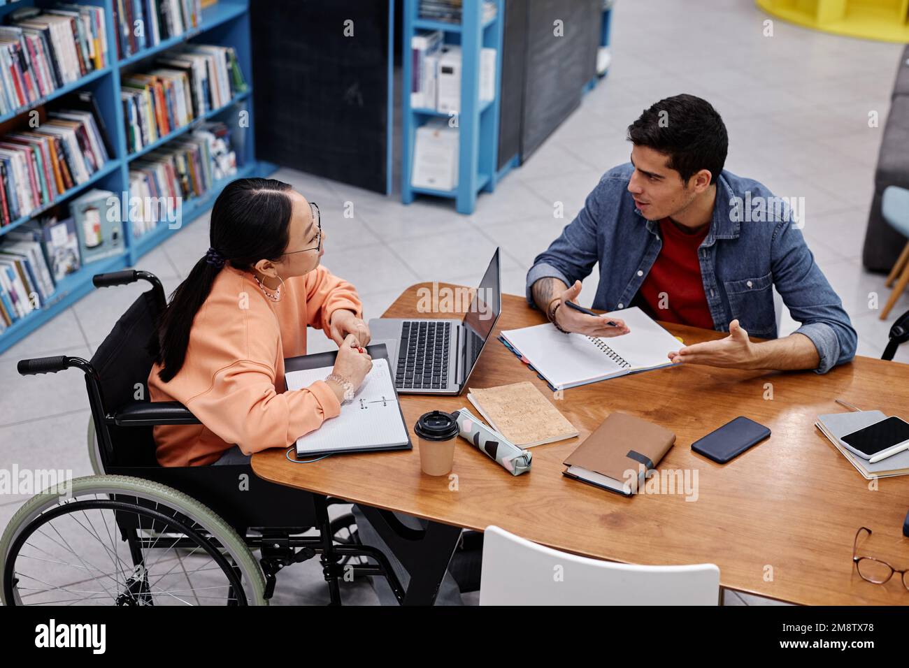 High angle portrait of Asian teenage girl with disability talking to ...