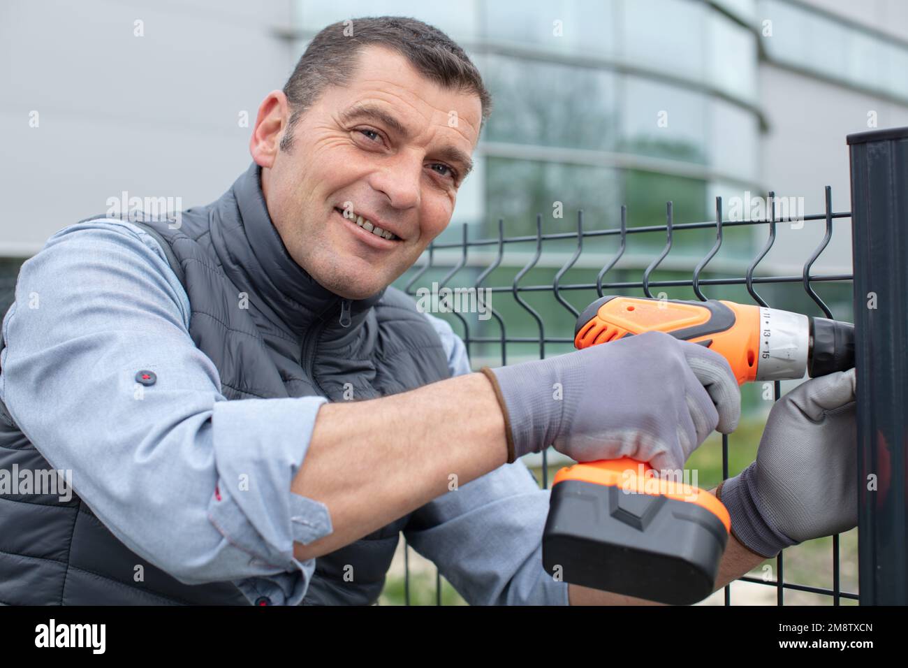 worker installing welded metal mesh fence Stock Photo - Alamy