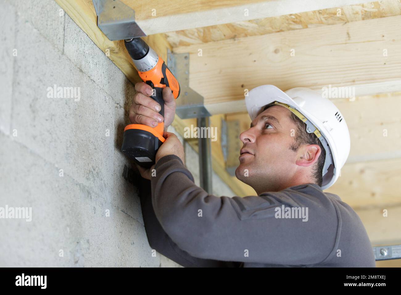 builder holding cordless drill in unfinished home Stock Photo - Alamy