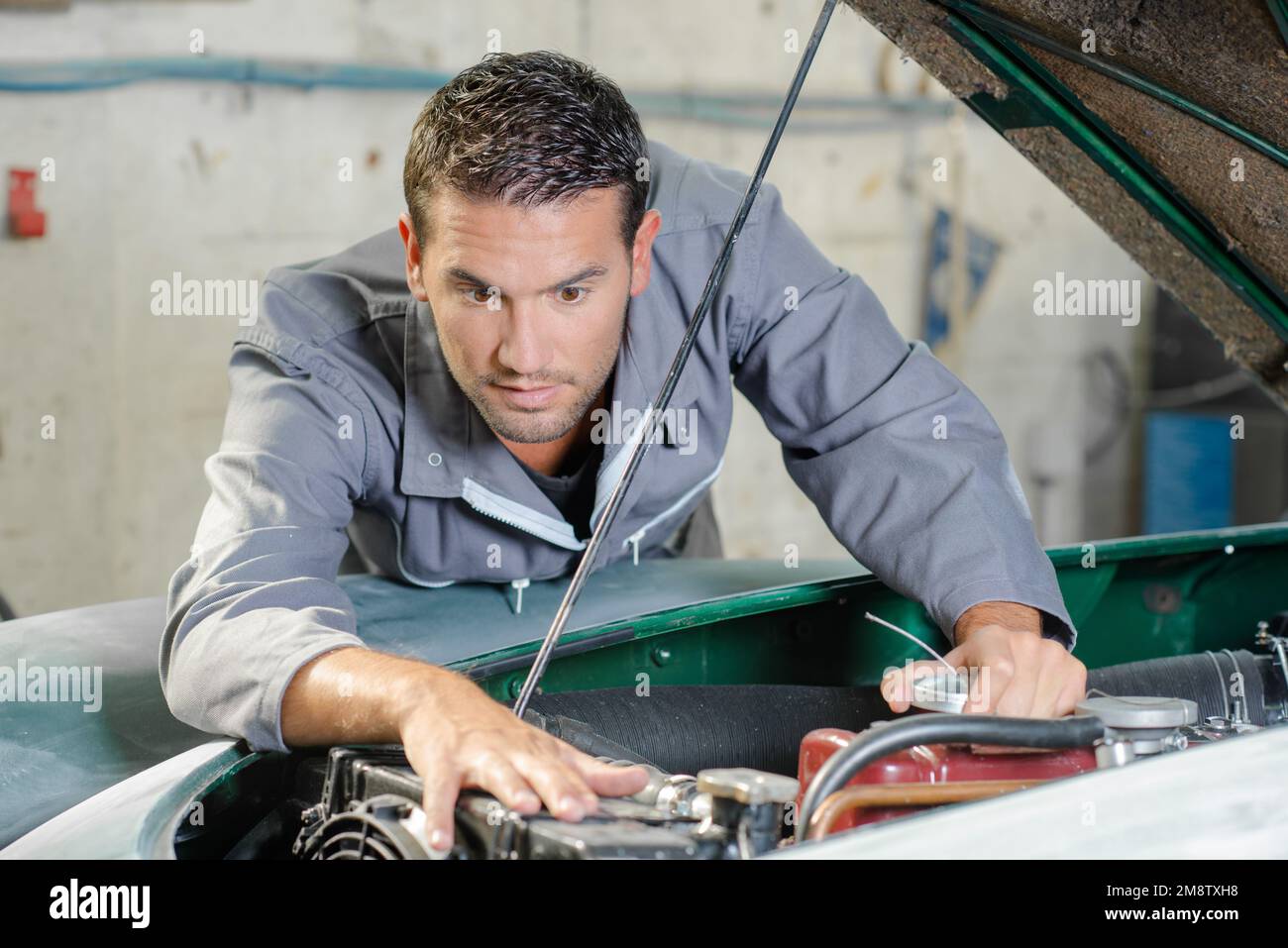 Young mechanic taking care of an engine Stock Photo - Alamy