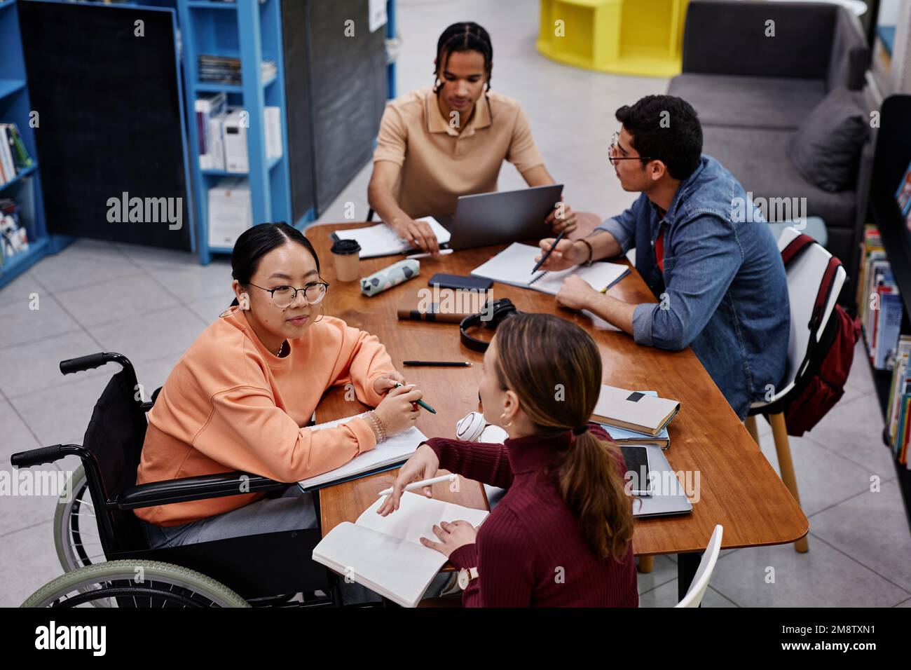 High angle view at diverse group of students at table in library ...
