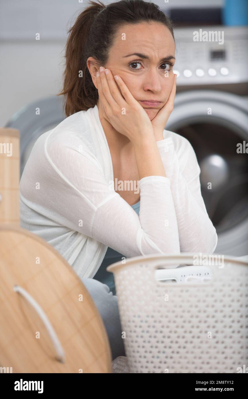 upset woman sitting at laundry room besides empty basket Stock Photo ...