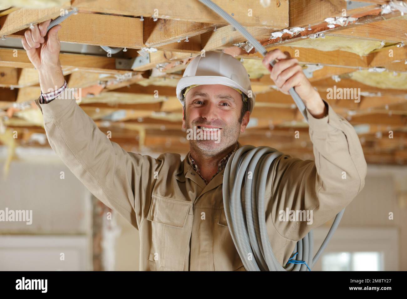 mature builder installing cable trunking in property Stock Photo - Alamy