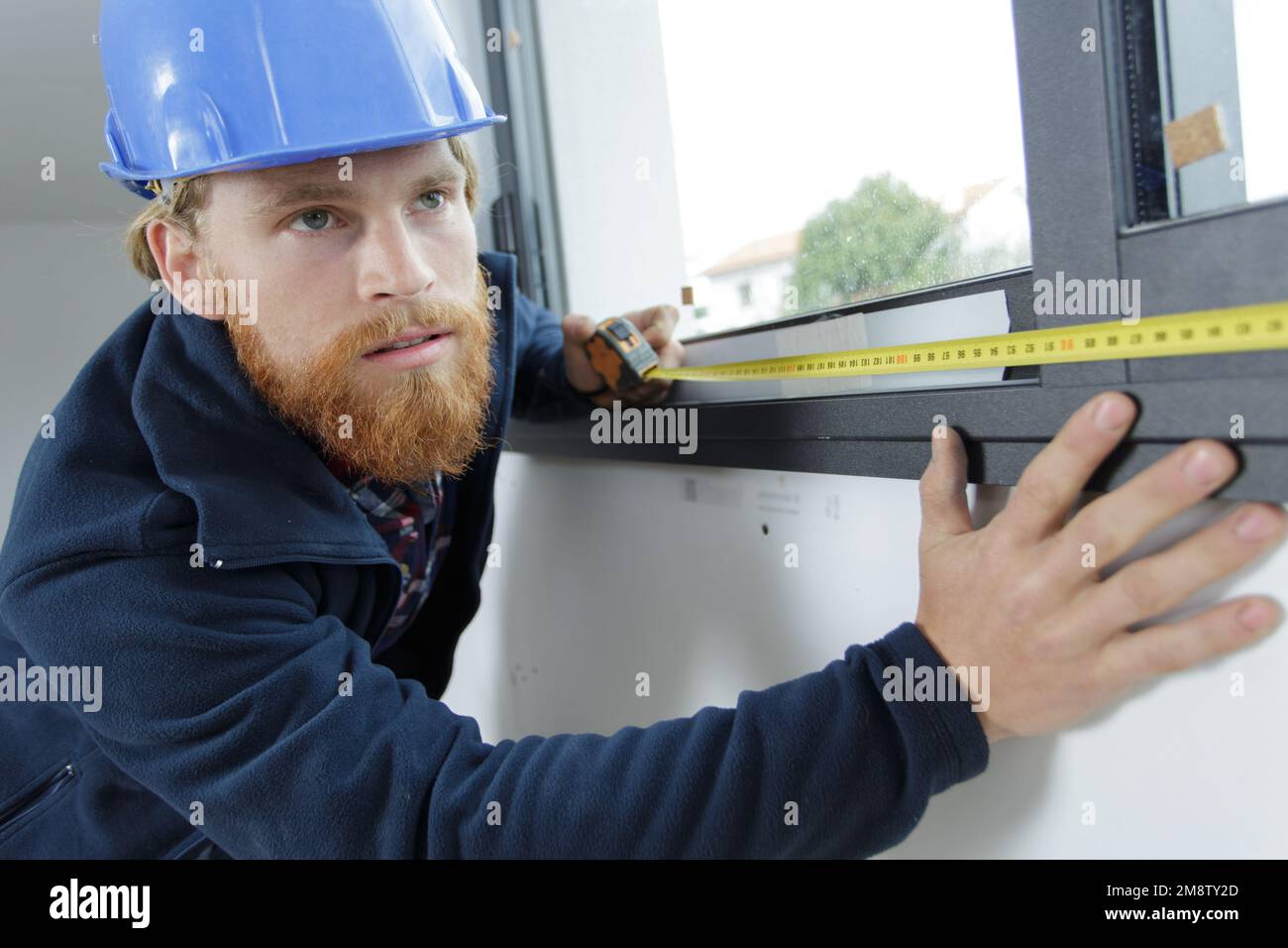builder measuring a window using a retractable tape measure Stock Photo ...