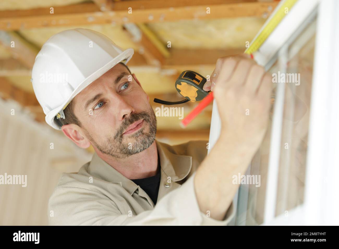 builder measuring a window using a tape measure and pencil Stock Photo ...