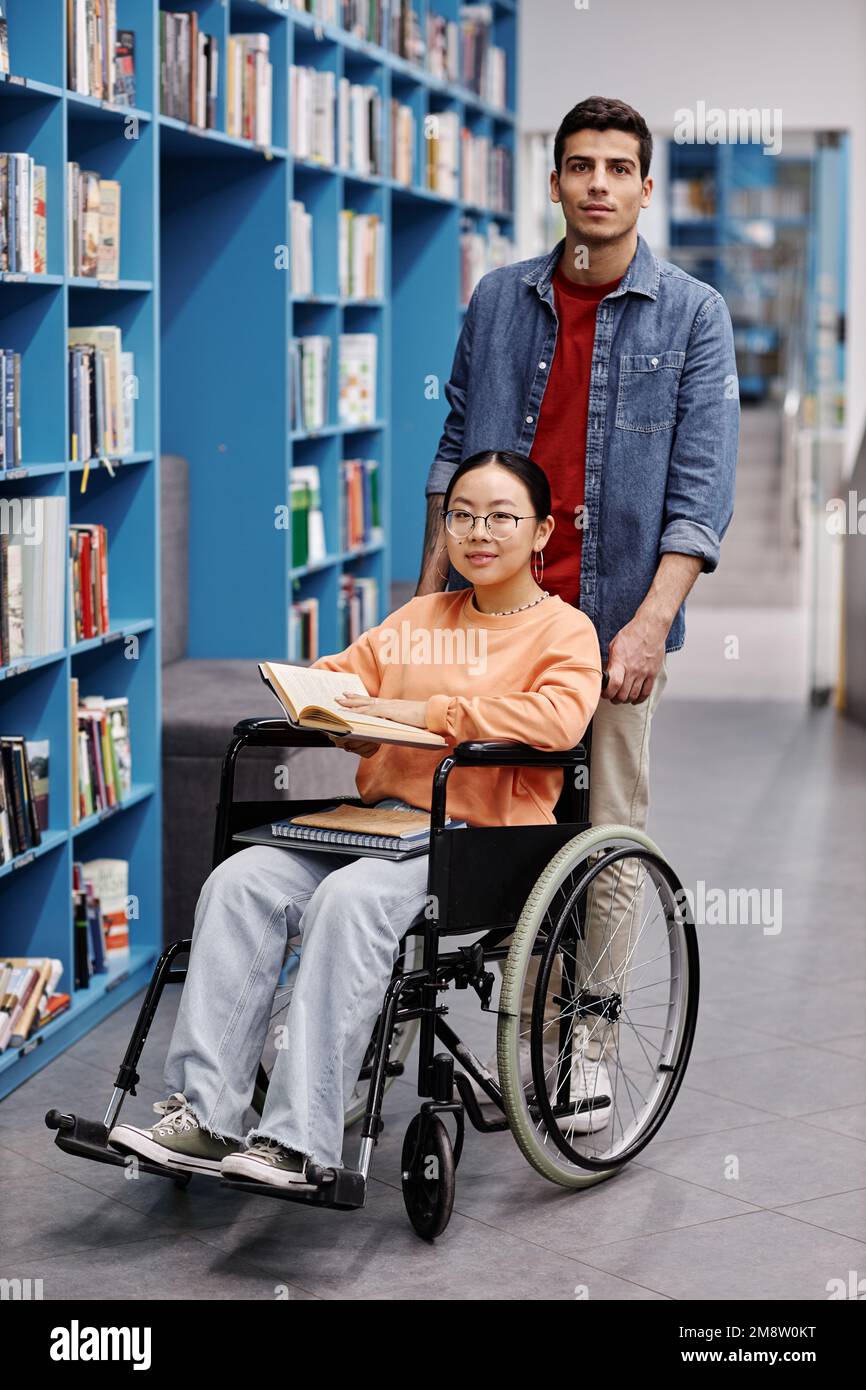 Full length portrait of smiling young man assisting female student with ...