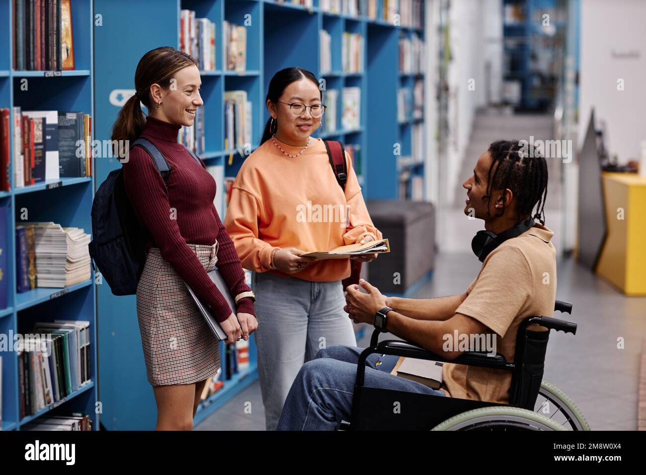 Side view portrait of young student with disability talking to friends ...