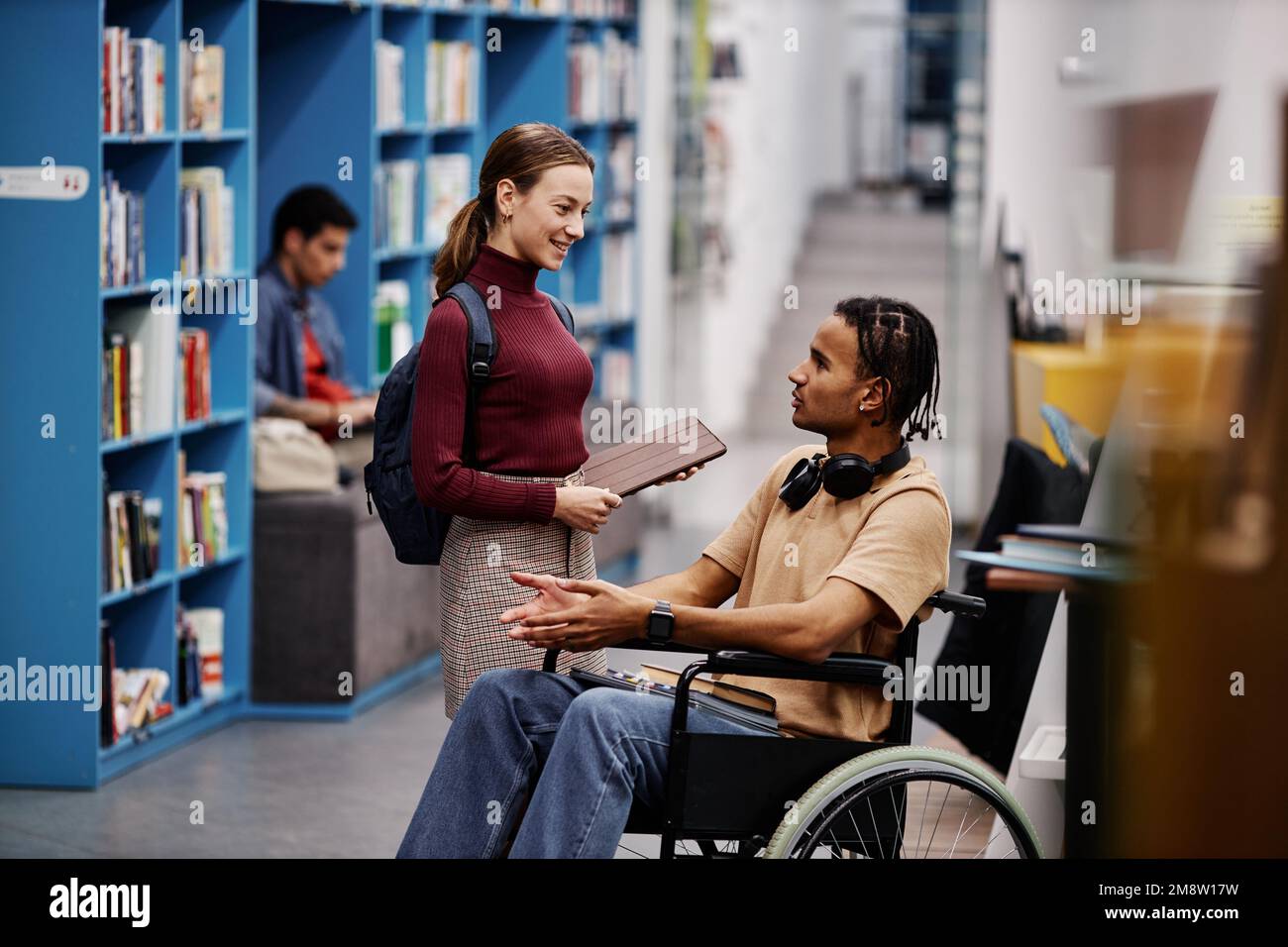 Side view portrait of young student with disability talking to friend ...