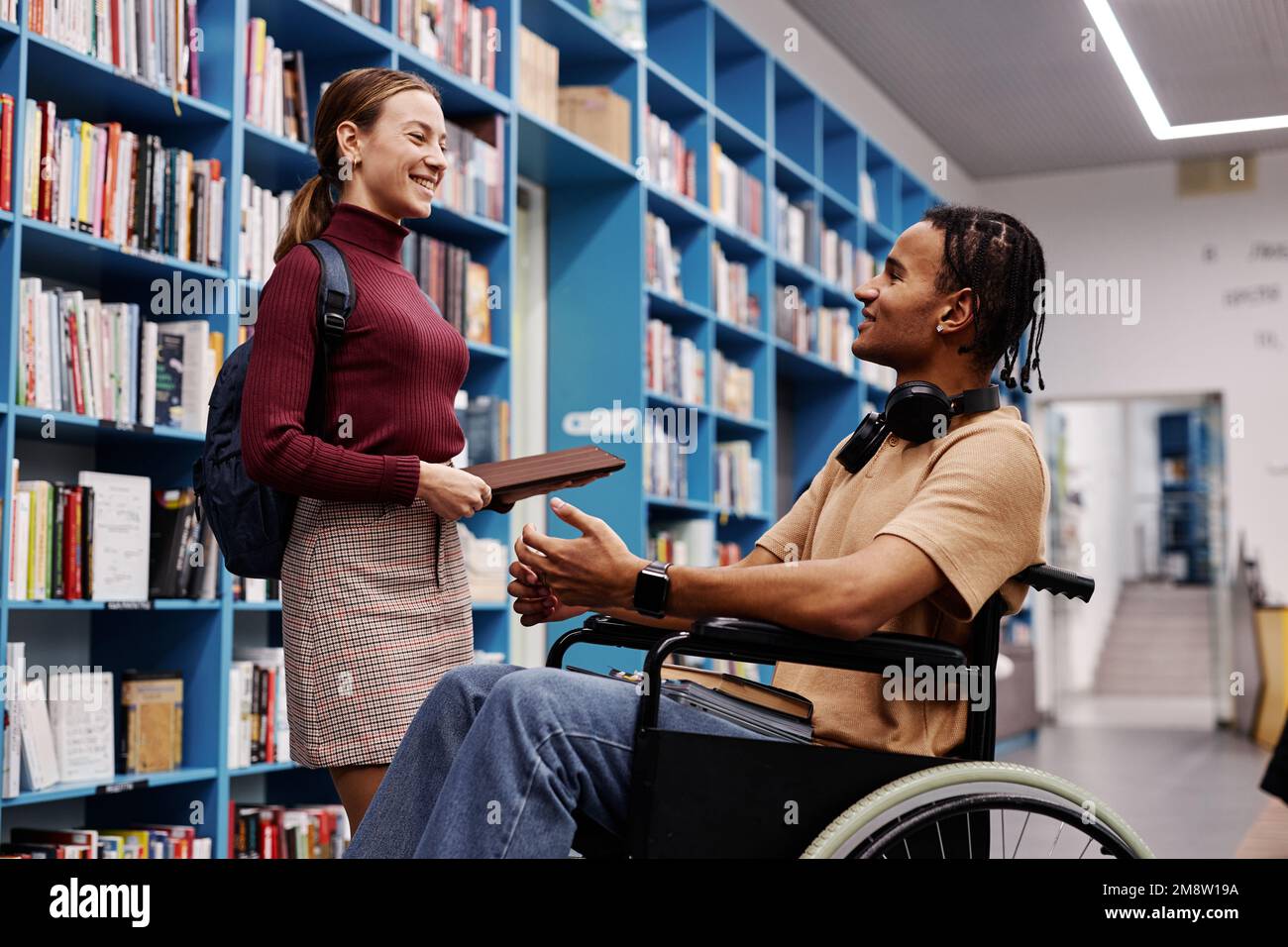 Side view portrait of black young student with disability talking to ...