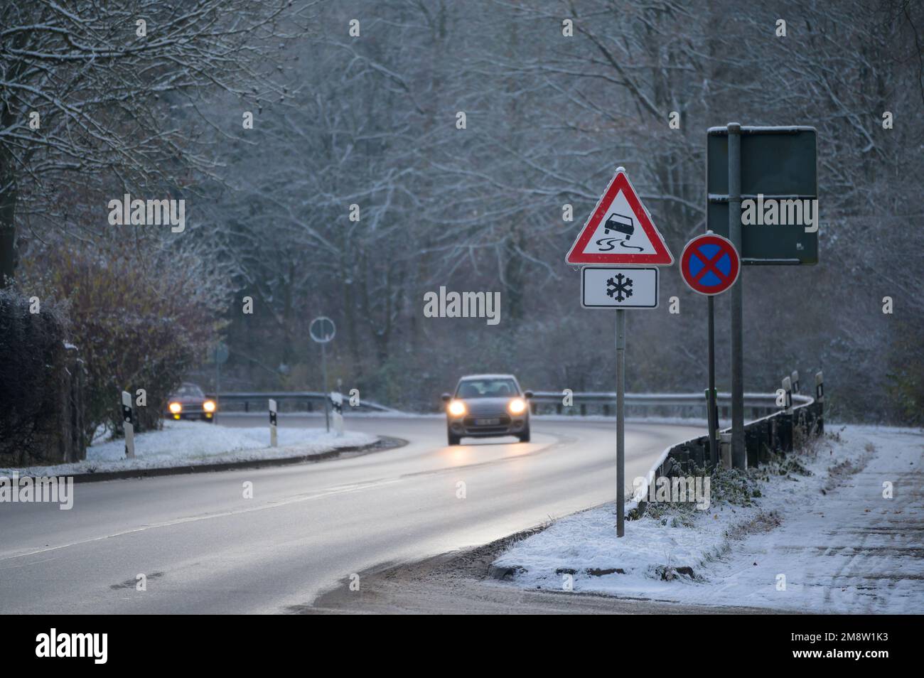 Cars driving down a wet road in winter with a slippery road and ice ...