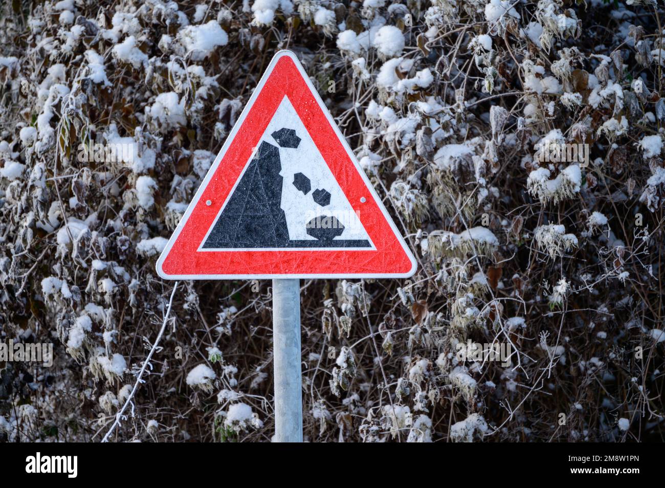 Falling rocks sign covered in ice and snow in front of snow covered ...
