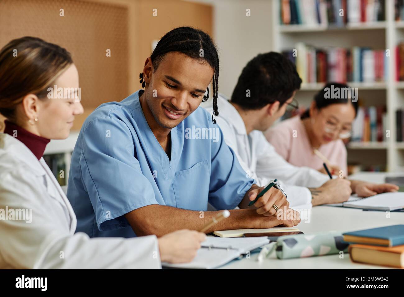 Diverse group of young medical professionals at table during meeting or ...