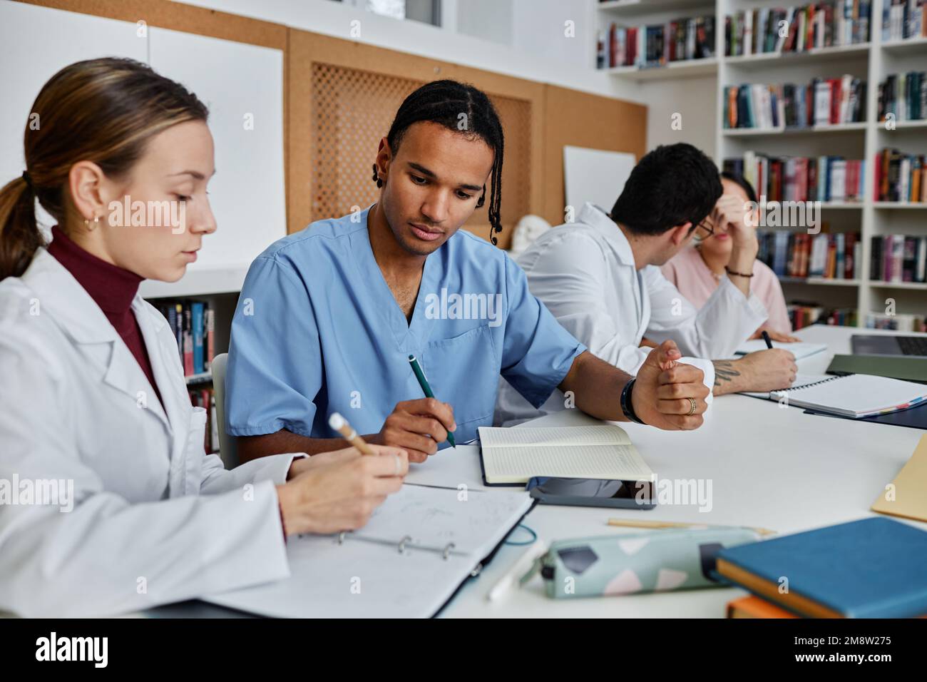 Diverse group of young medics and nurses working at table during ...