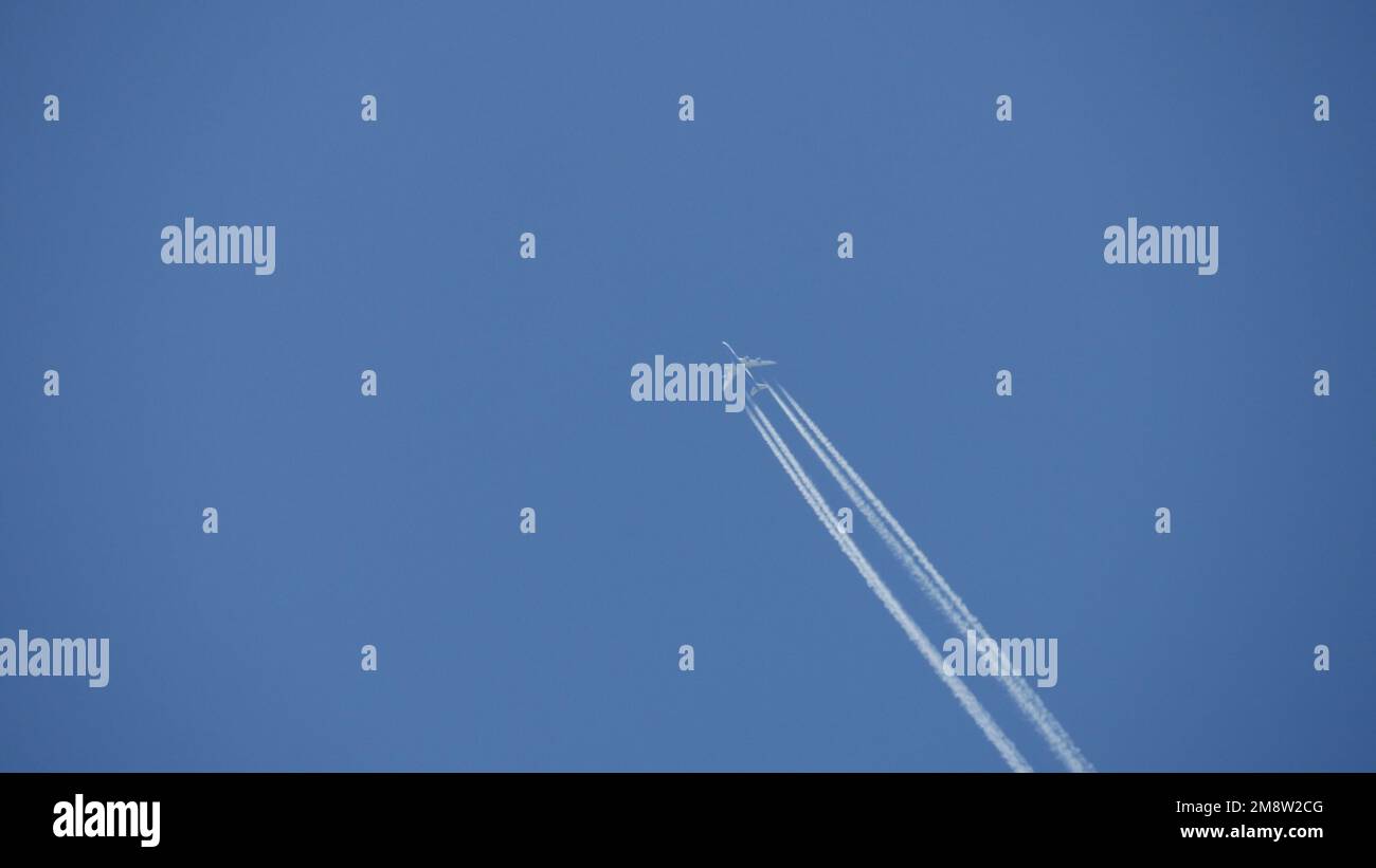 Passenger jet flying high with contrails Stock Photo - Alamy