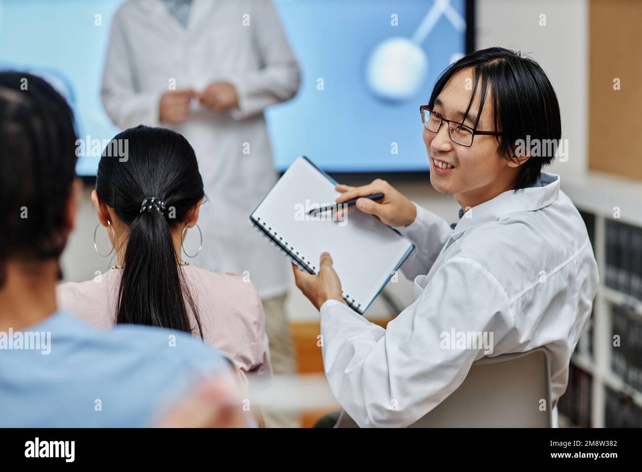Portrait of smiling asian doctor talking to colleague in audience at ...