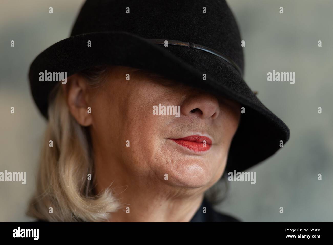 Studio portrait of a mature lady in a black hat pulled over her eyes ...