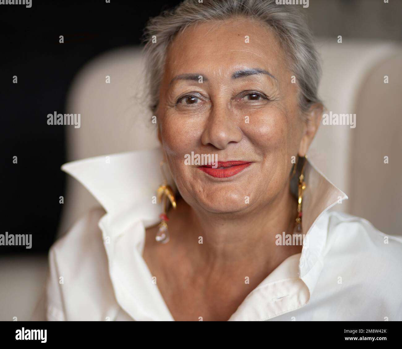 Charming lady in a loose white shirt with a hairstyle looks at the ...