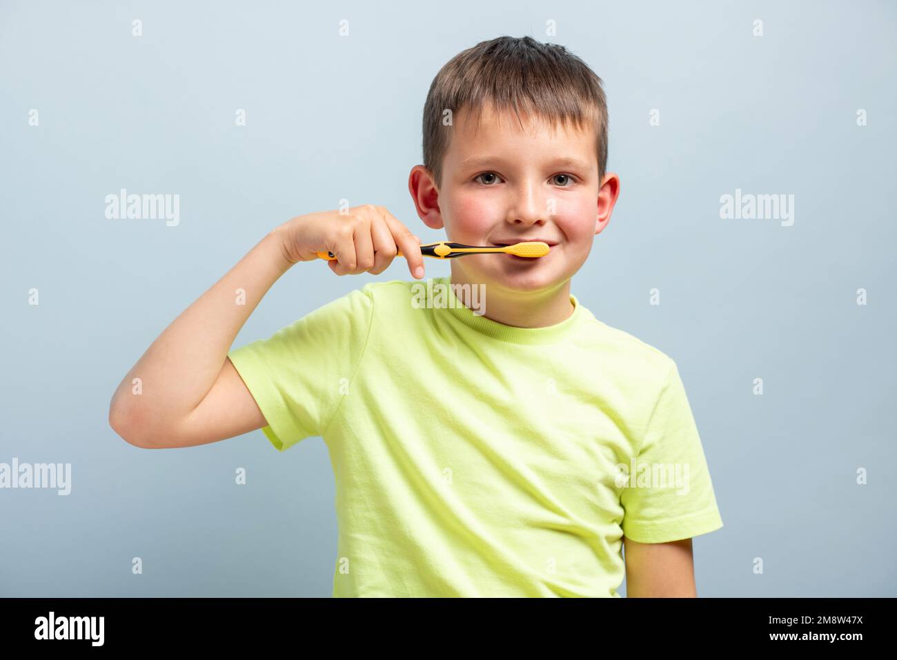 Kid boy brushing his teeth on blue background. The concept of daily ...