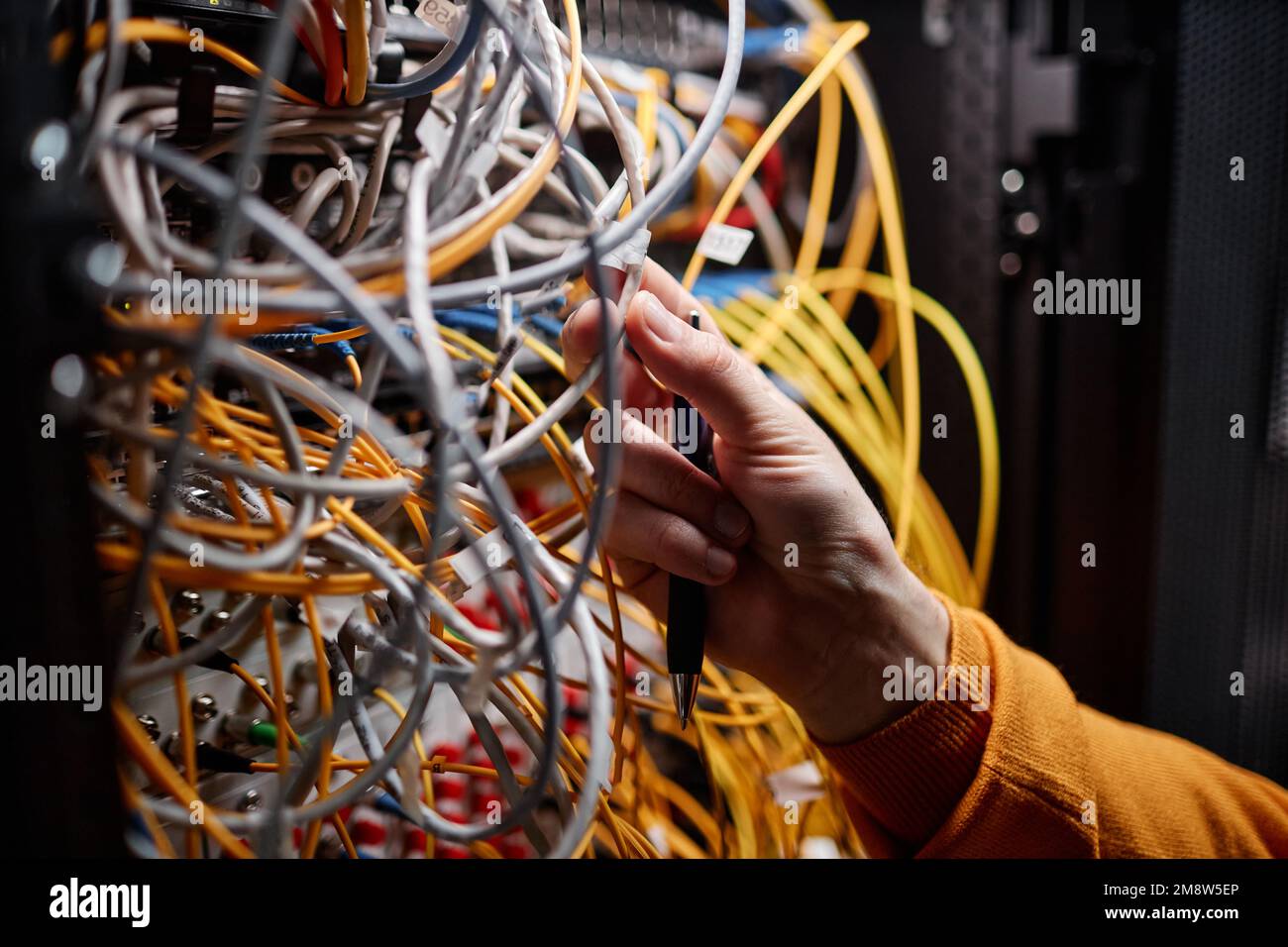 Close up of technician connecting cables and wires in server cabinet while setting up internet ...