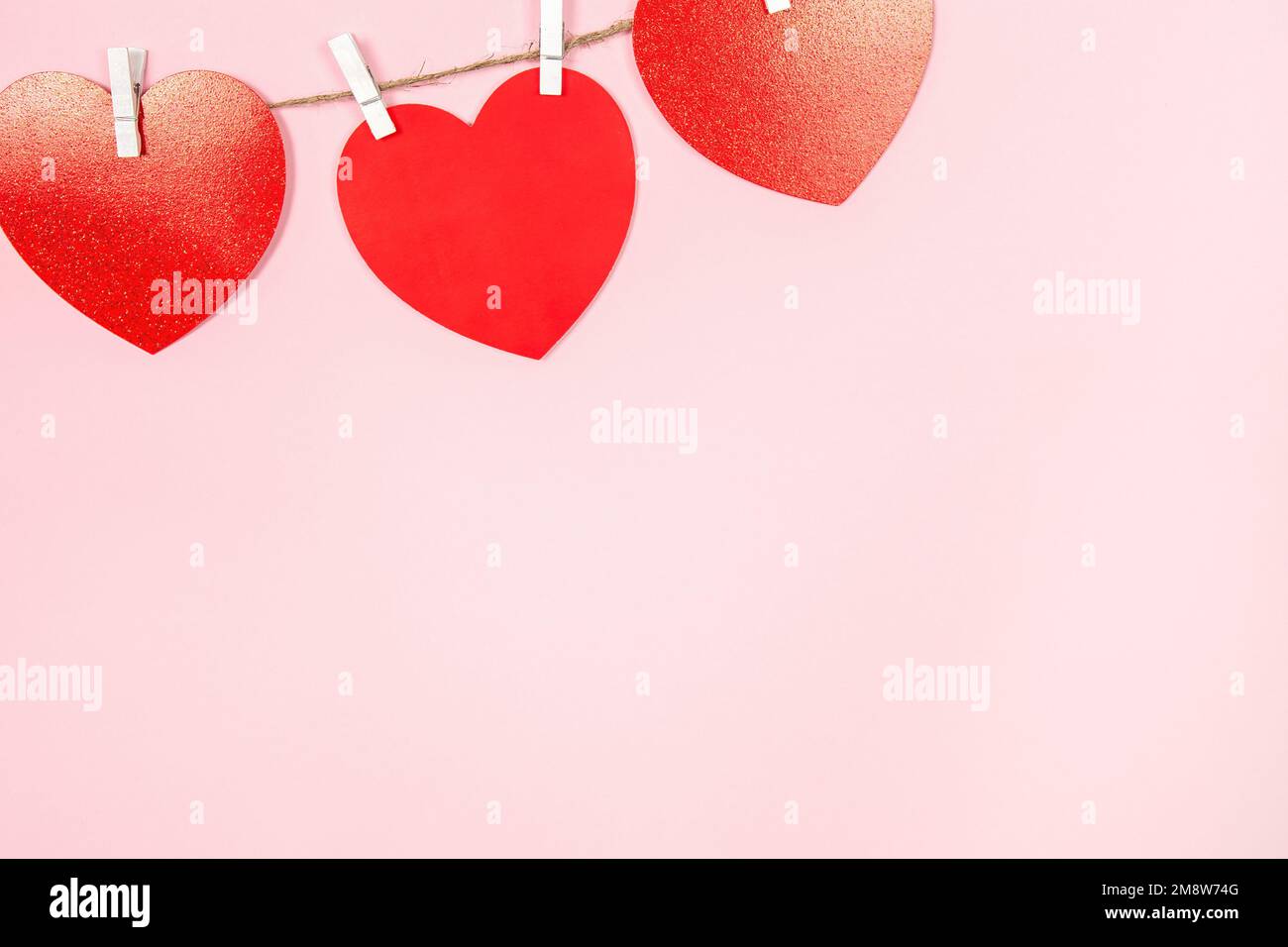 Garland of red hearts on clothespins on a pink background. Copy space ...