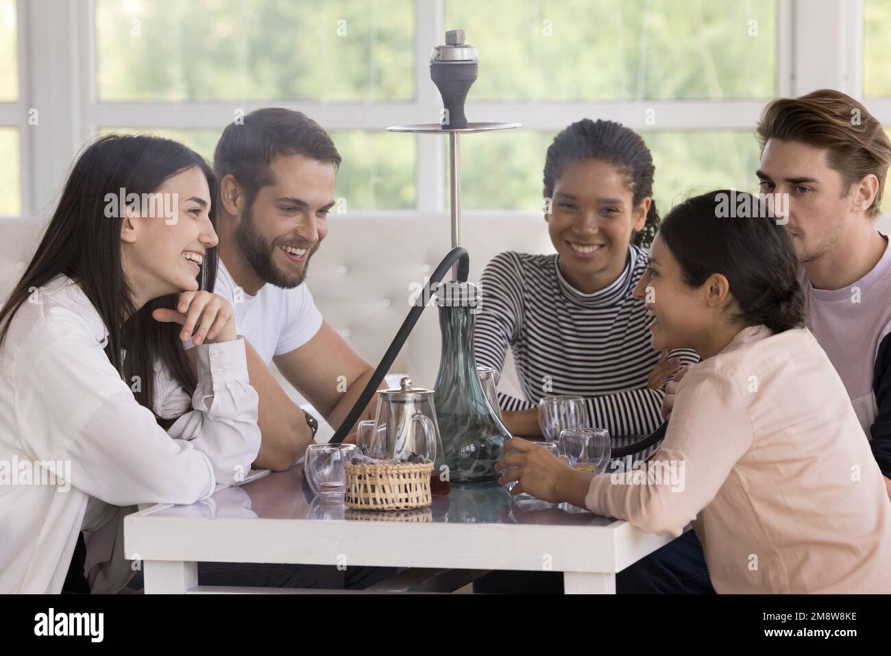 Multiracial group of happy cheerful young friends smoking hookah Stock ...