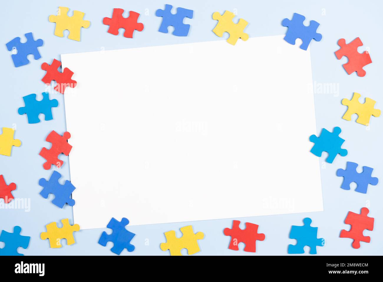 Blank white paper card with blue, yellow, red pieces of puzzle on light ...